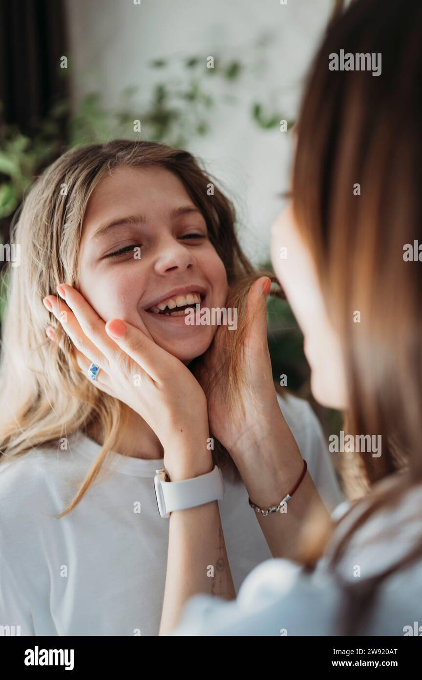 Mother touching happy daughter's cheeks at home Stock Photo - Alamy