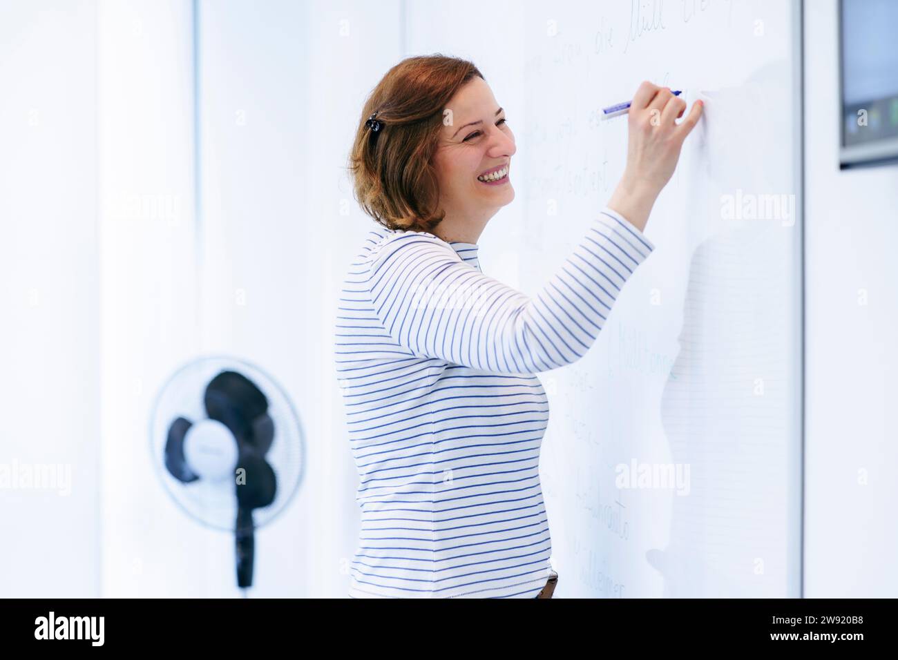 Happy teacher writing on whiteboard and teaching in classroom Stock ...
