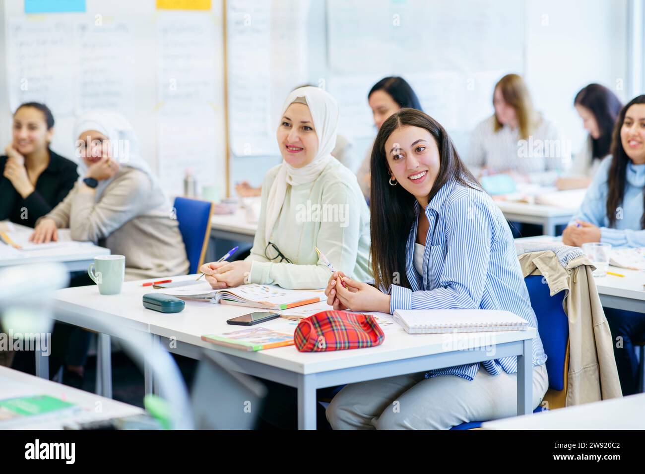 Smiling multi-ethnic students at desk learning in classroom Stock Photo - Alamy