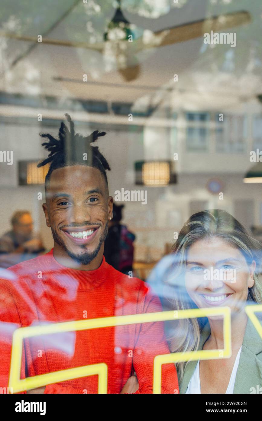 Smiling multiracial business colleagues looking through window Stock ...