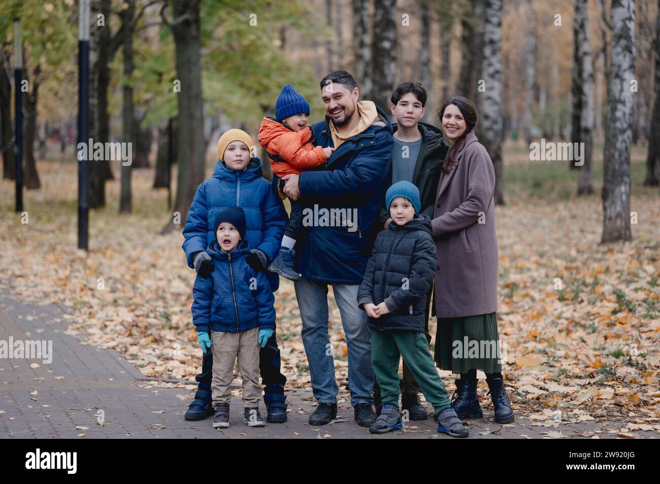 Happy family together standing in front of trees at park Stock Photo ...