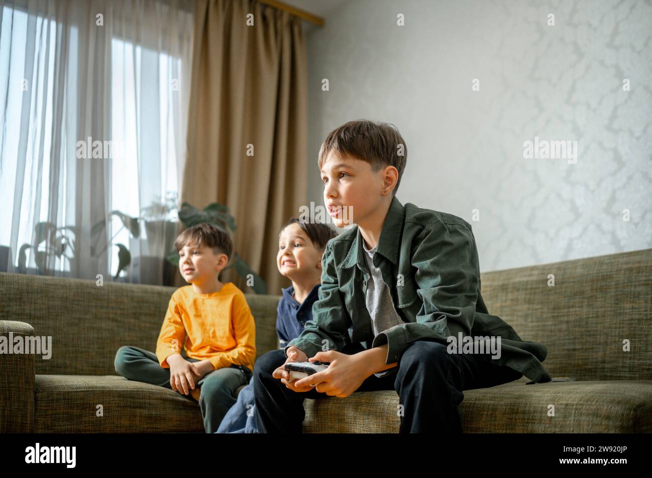 Brothers playing video game sitting on sofa at home Stock Photo - Alamy