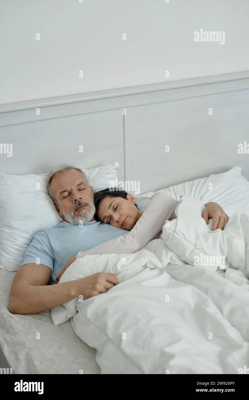 Wife Cuddling Her Husband While Sleeping Together In Bed Stock Photo