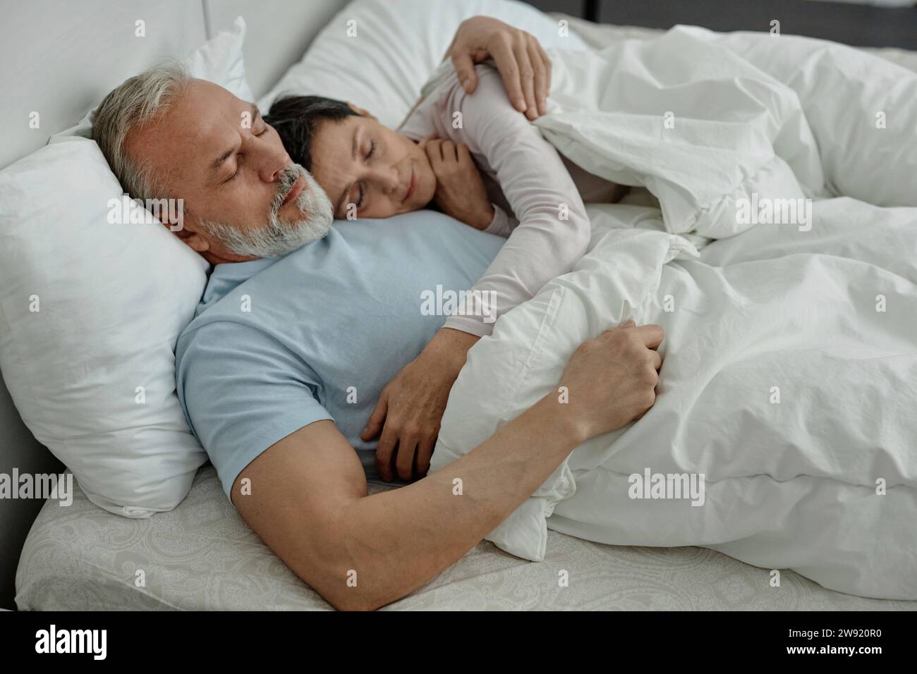 Couple cuddling each other during sleep in bed Stock Photo - Alamy