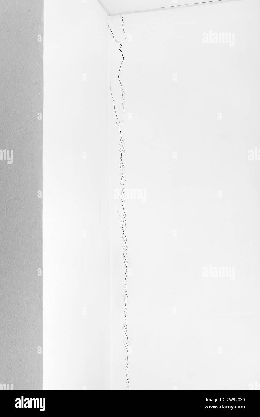 Deep crack in the white wall from floor to ceiling. Problems of ...