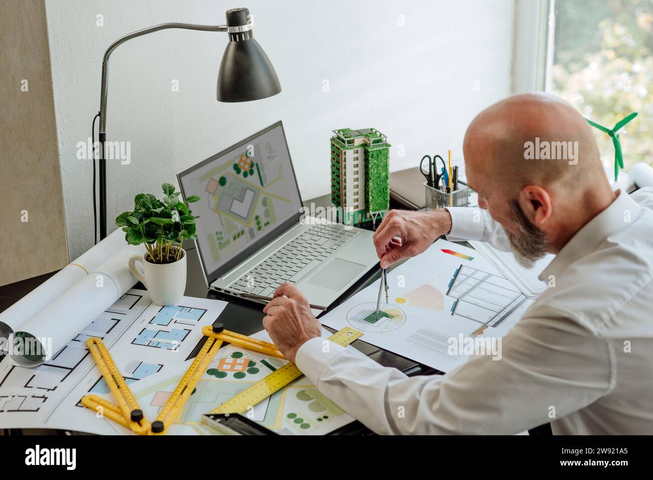 Architect working on blueprint with drawing compass at desk Stock Photo ...