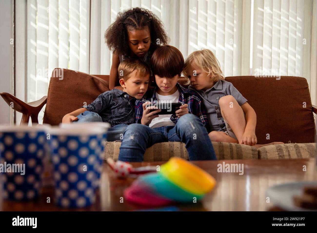 Boy playing game on smart phone with friends sitting on couch Stock ...