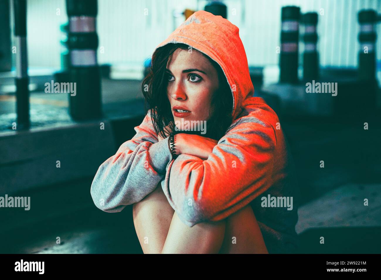 Scared woman hugging knees and sitting in garage Stock Photo - Alamy