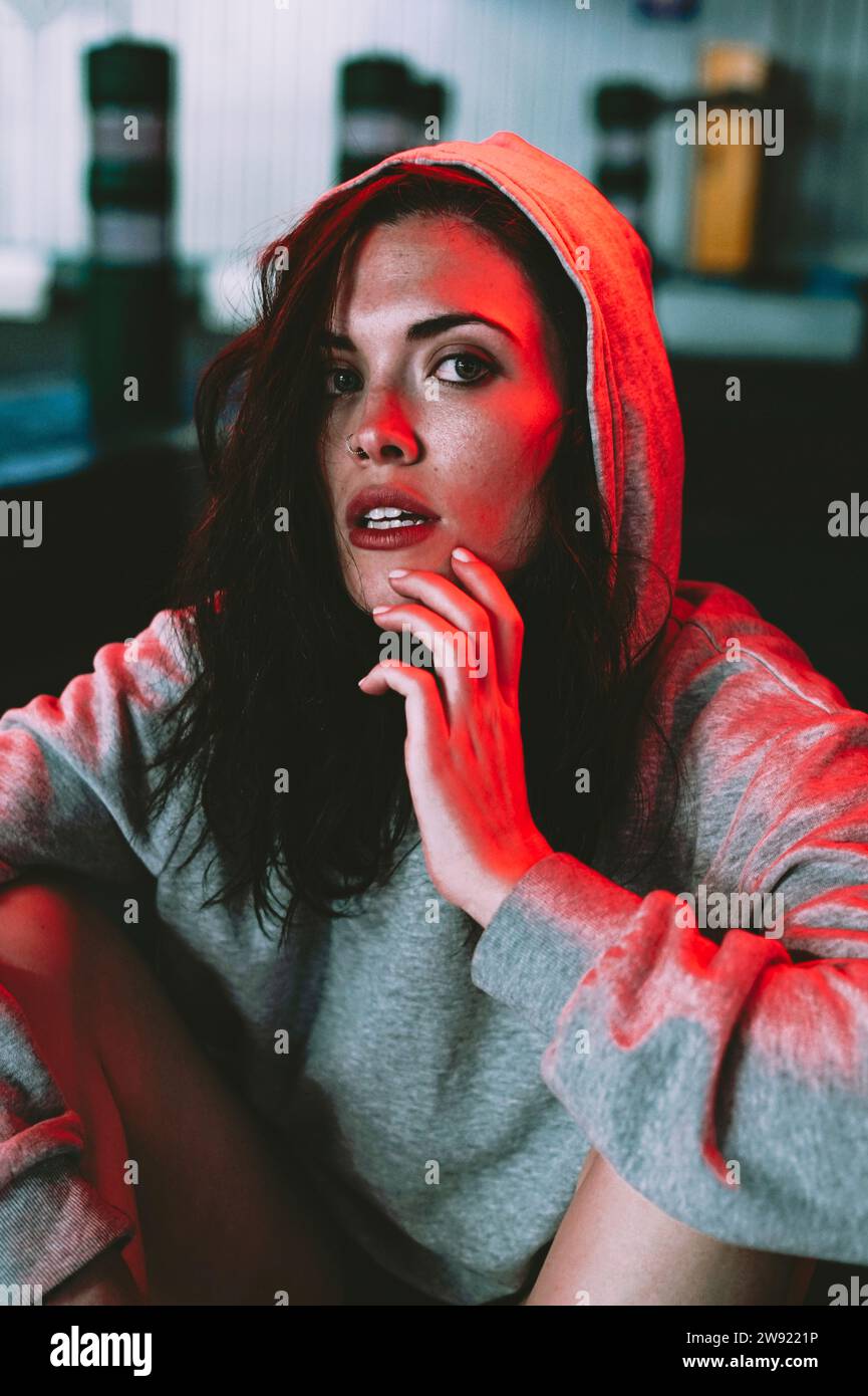 Woman wearing hooded shirt sitting under neon lights Stock Photo - Alamy
