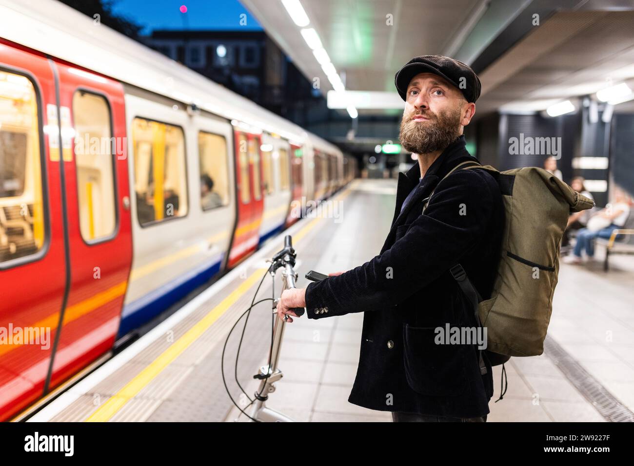 Mature man holding cycle and waiting for train at station Stock Photo ...