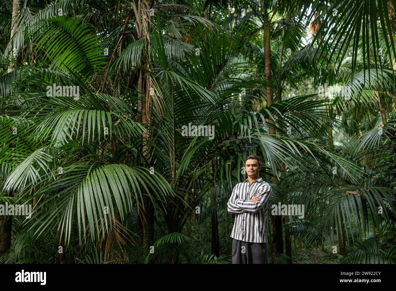 Man standing with arms crossed in front of palm trees Stock Photo - Alamy