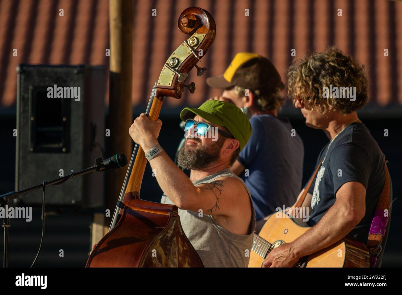 An acoustic three piece on stage play in the evening sun at the 2019 ...