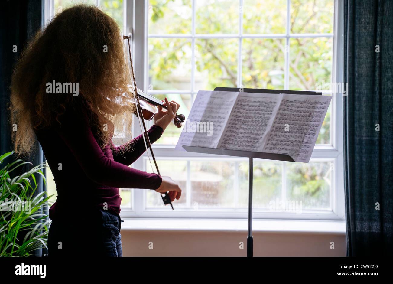 Girl practicing violin in front of window at home Stock Photo - Alamy