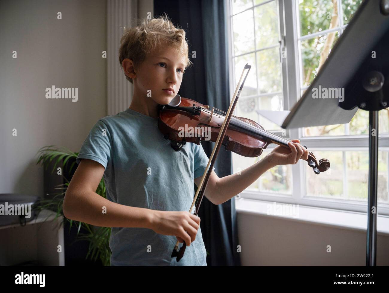 Elementary boy playing violin near window at home Stock Photo - Alamy