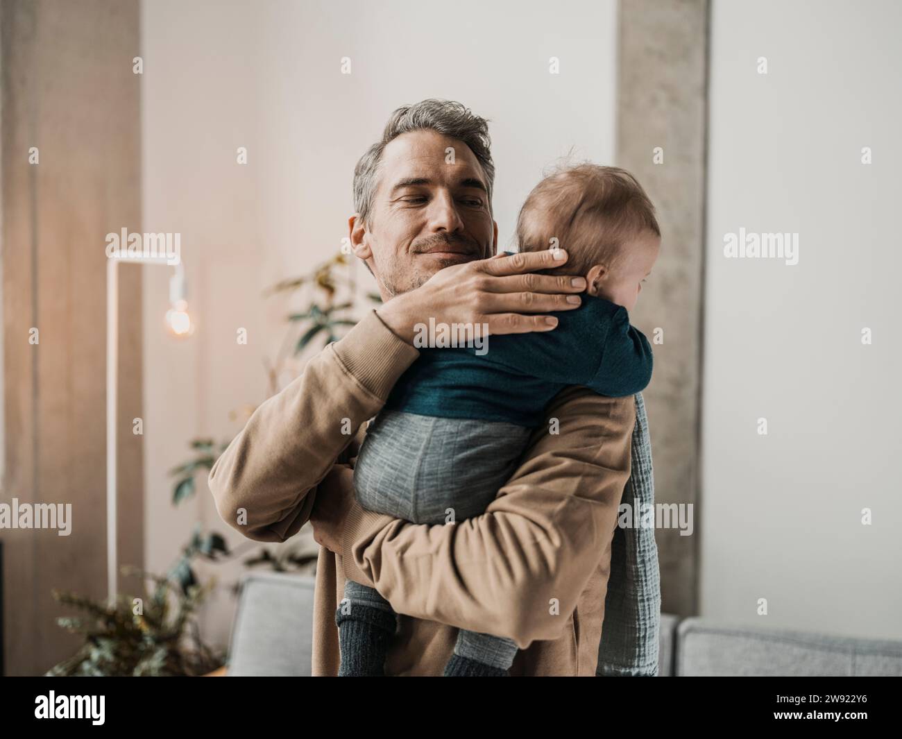 Smiling father embracing boy in arms at home Stock Photo - Alamy