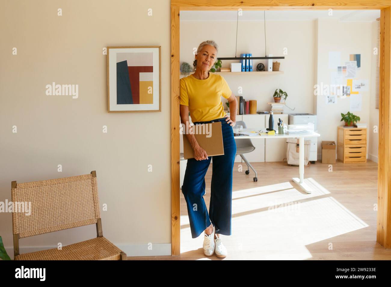 Businesswoman standing with hand on hip and holding file folder in ...