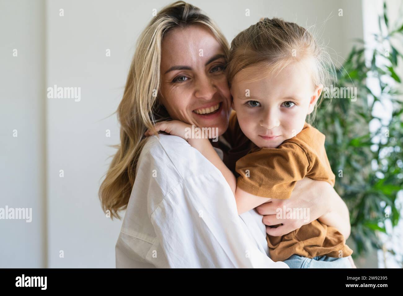 Happy blond mother embracing boy at home Stock Photo - Alamy