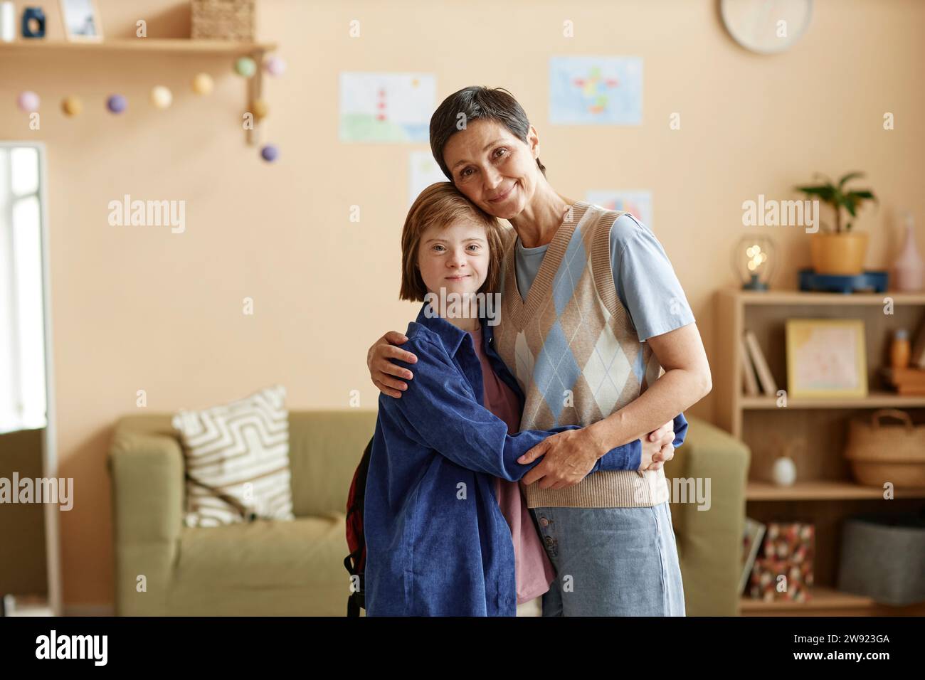 Mother and her daughter with Down syndrome embracing each other at home ...