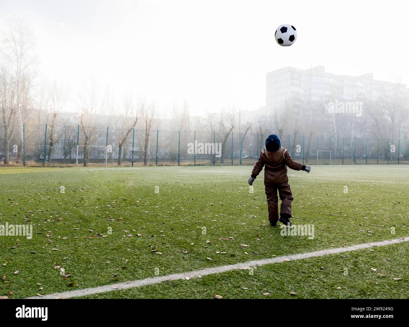 Boy throwing ball in air at soccer field Stock Photo - Alamy