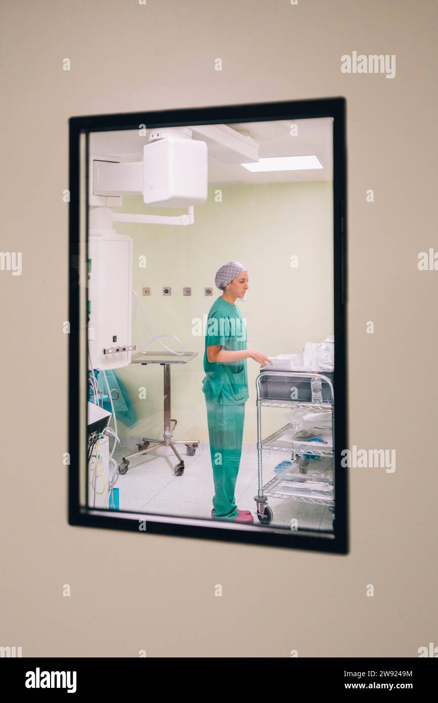 Nurse in operating room seen through glass window Stock Photo - Alamy