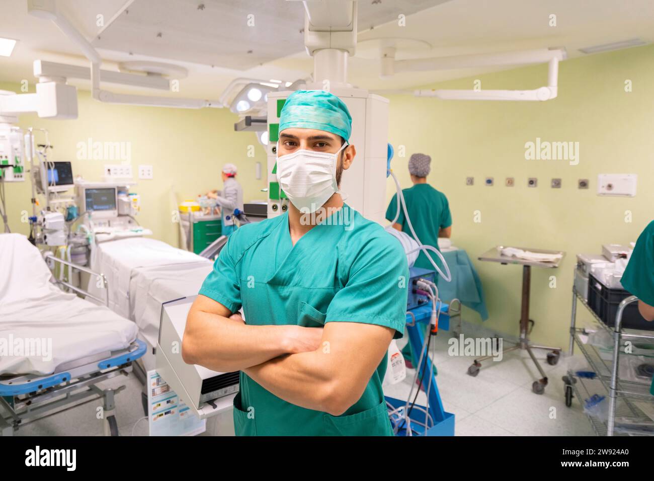 Surgeon wearing mask standing with nurse working in background at ...