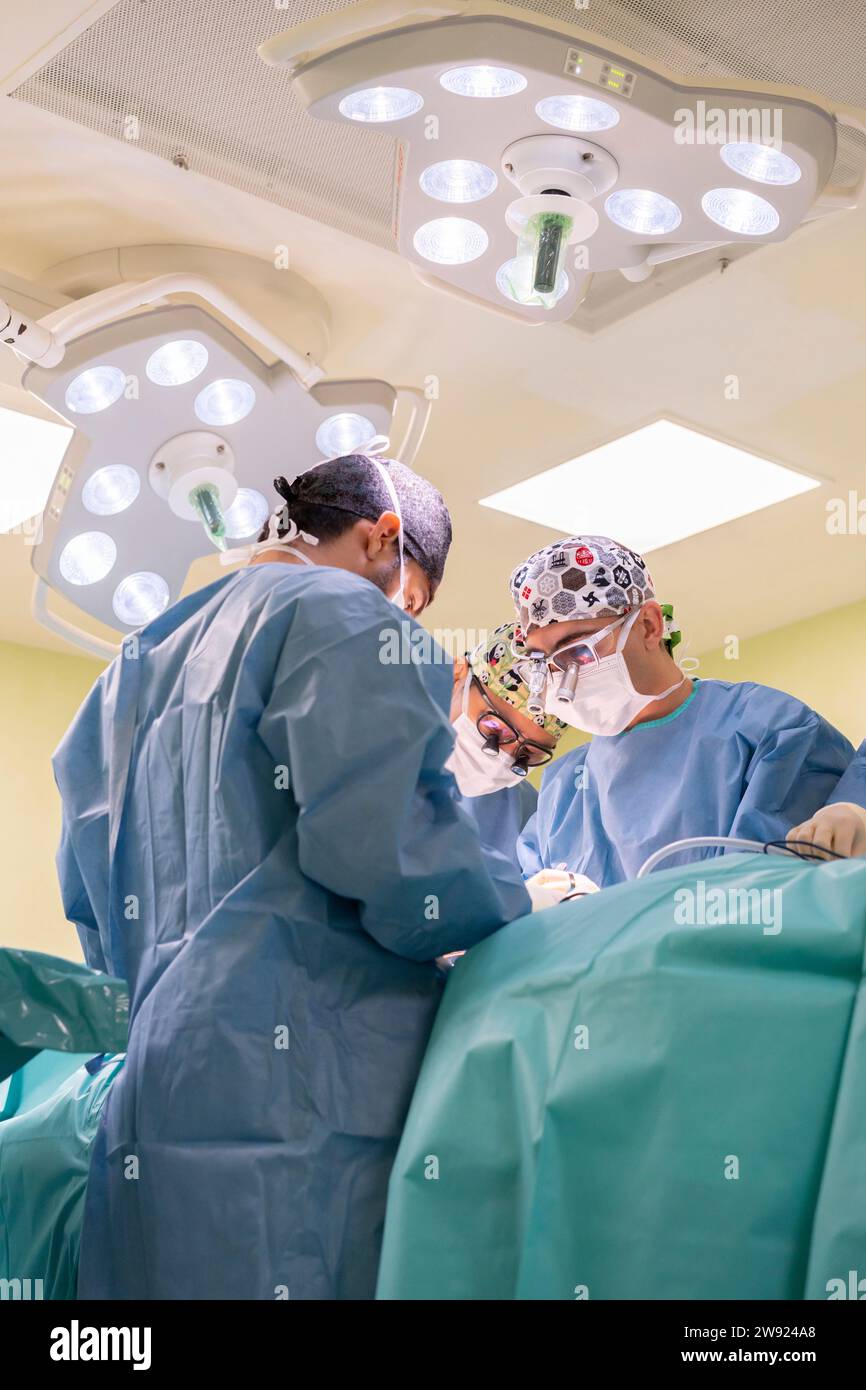 Surgeon and nurses performing surgery on patient under surgical light ...