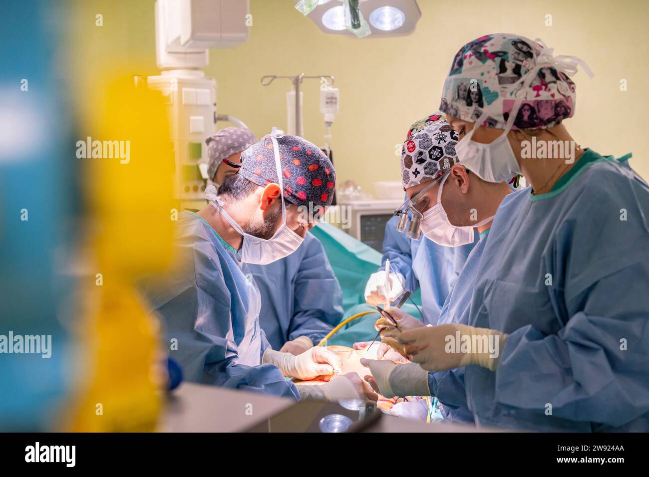 Team of surgeons wearing masks performing surgery on patient in ...