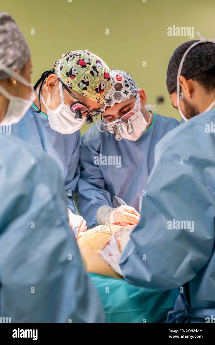 Surgeons performing surgery on patient in operating room at hospital ...