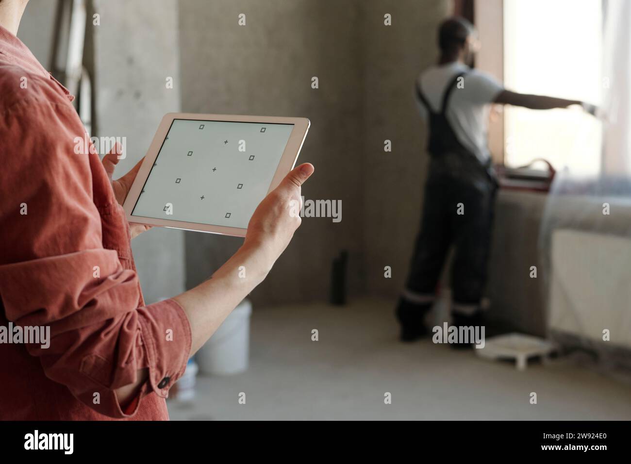 Engineer holding tablet PC with coworker in background at construction ...
