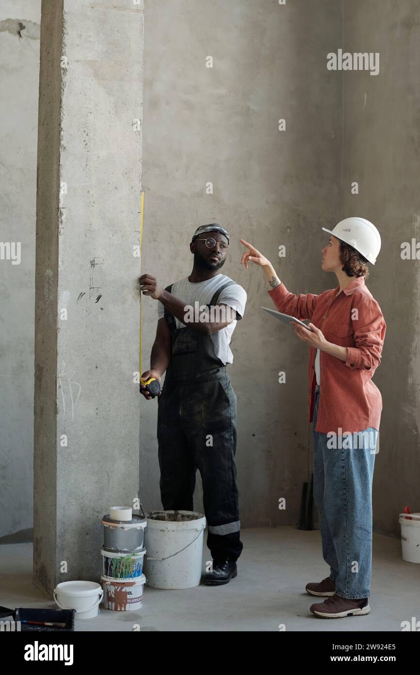 Building contractor giving instructions to coworker at construction ...