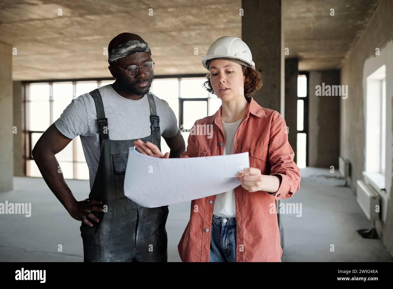 Engineer having discussion over blueprint with construction worker at ...