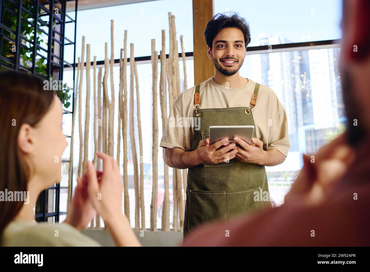 Smiling waiter taking food orders from customers at restaurant Stock ...
