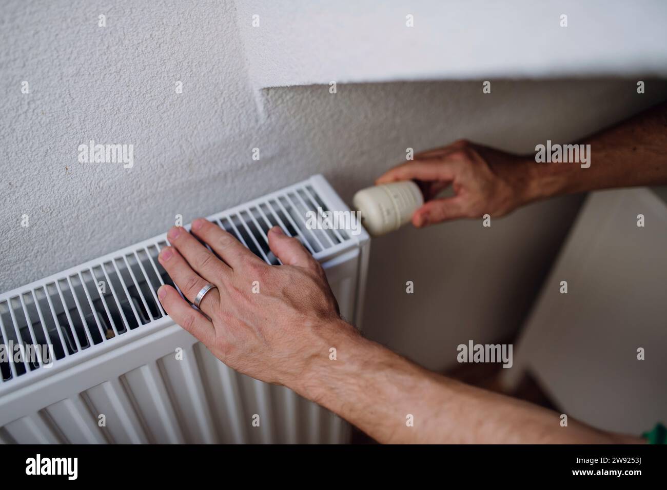 Man adjusting radiator with regulator near wall Stock Photo - Alamy
