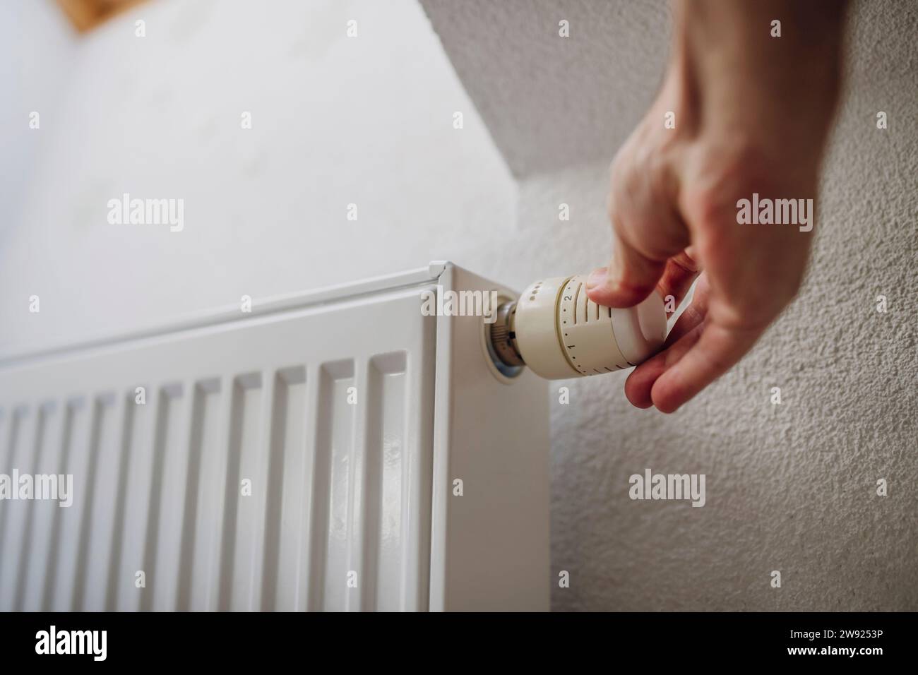 Hand of man adjusting radiator near wall Stock Photo - Alamy