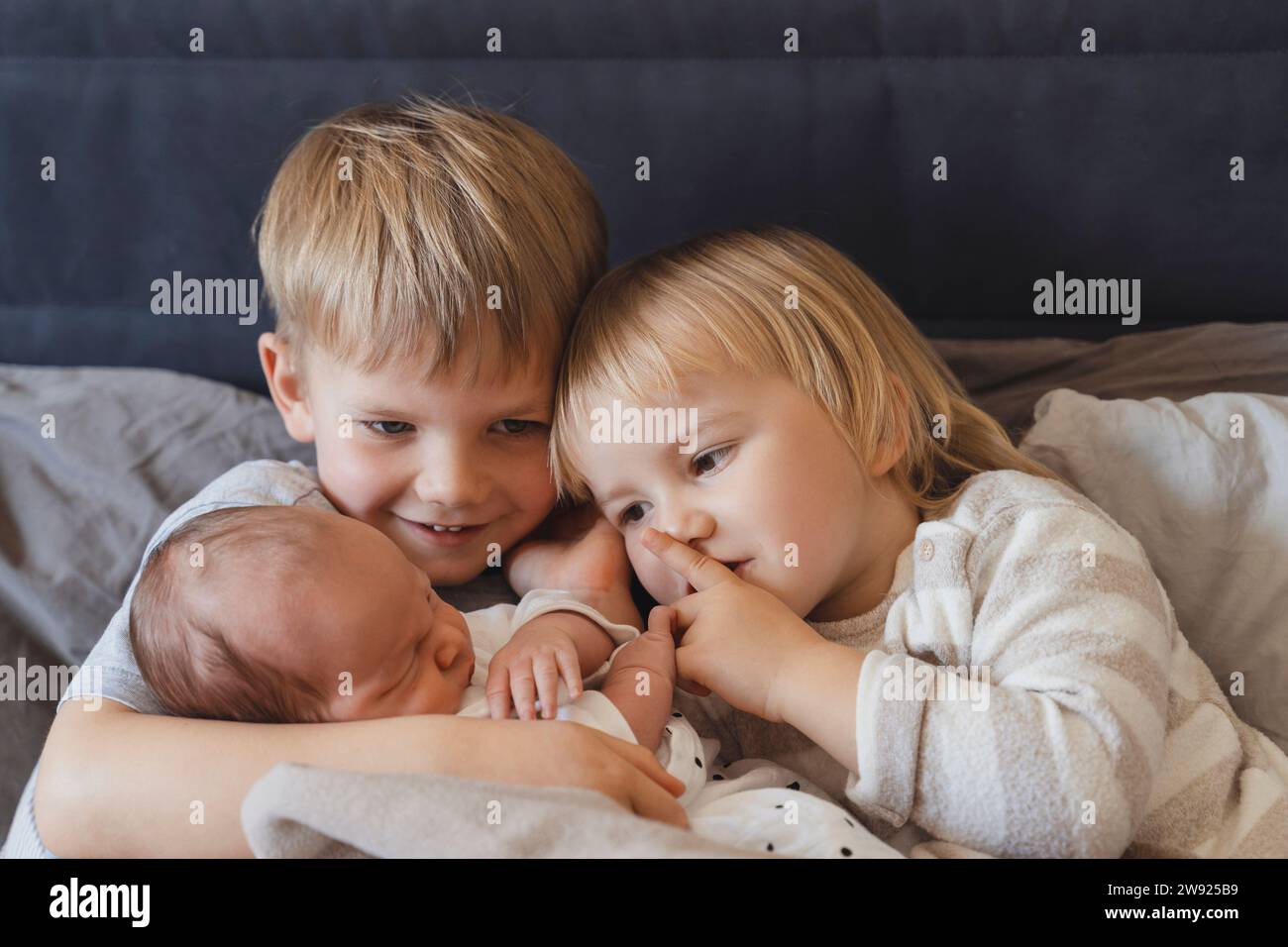 Siblings holding baby boy in arms at home Stock Photo - Alamy