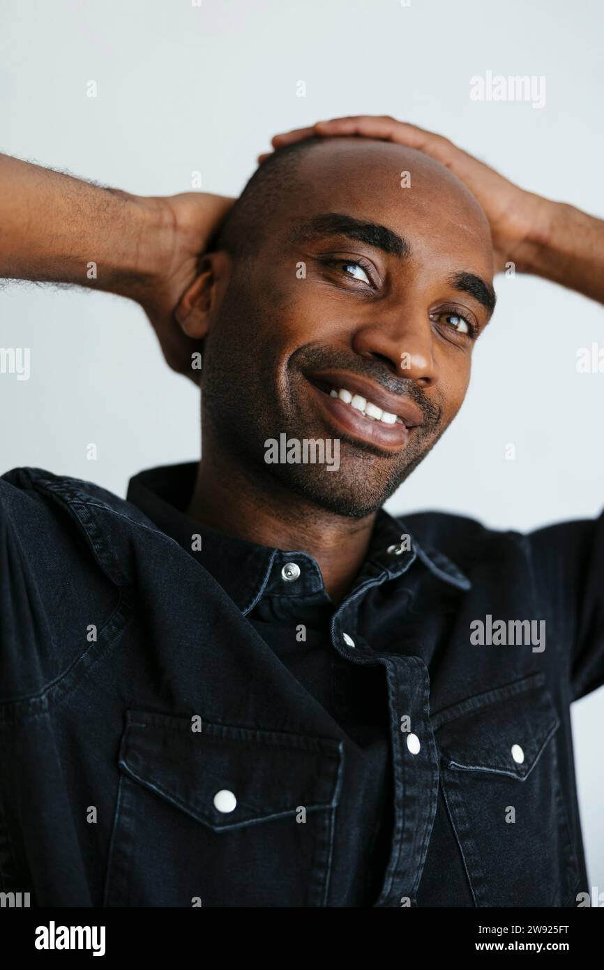 Smiling man touching head against white background Stock Photo - Alamy