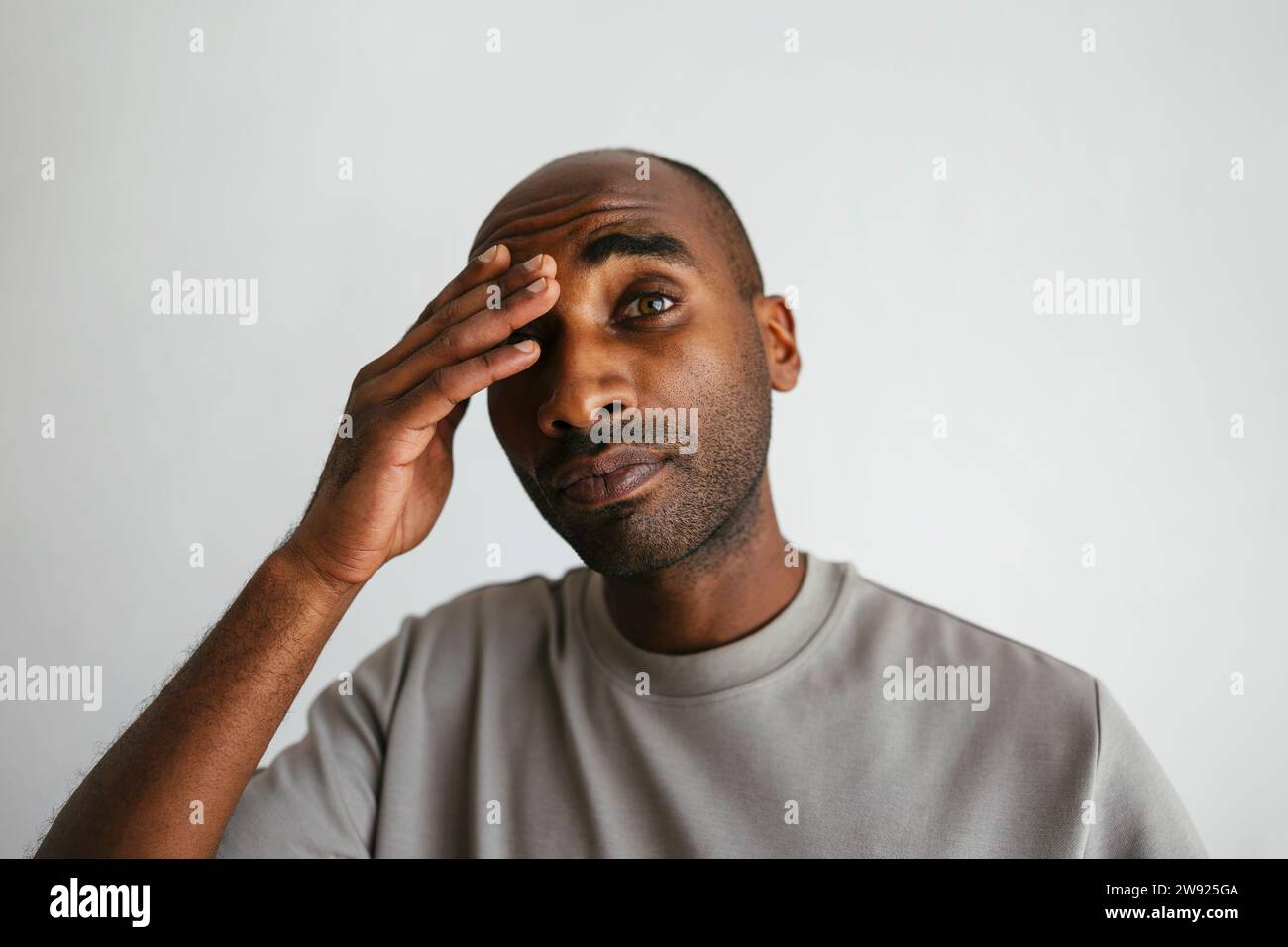 Man with head in hand against white background Stock Photo - Alamy