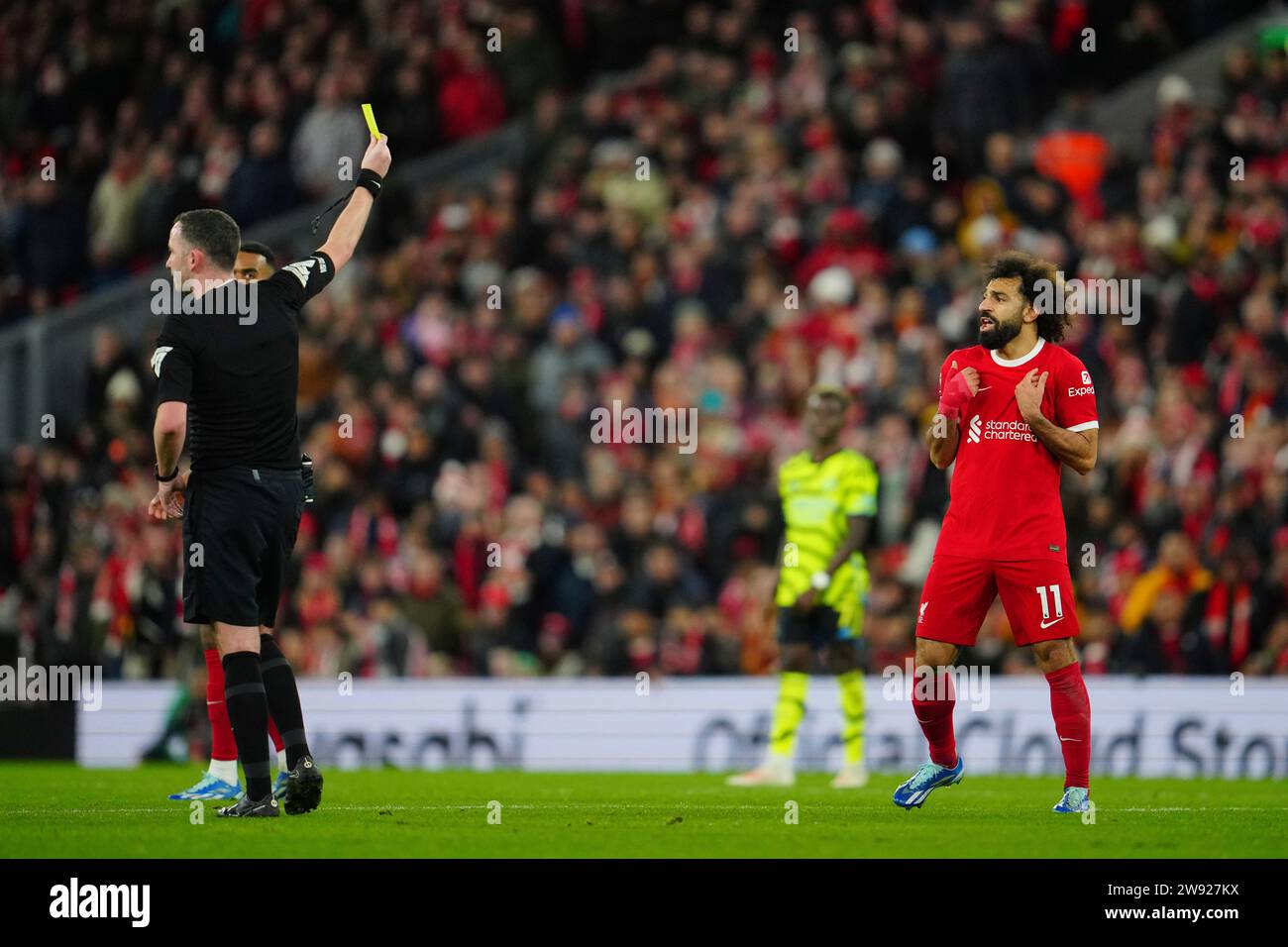 Referee Chris Kavanagh, left, shows a yellow card to Liverpool's ...