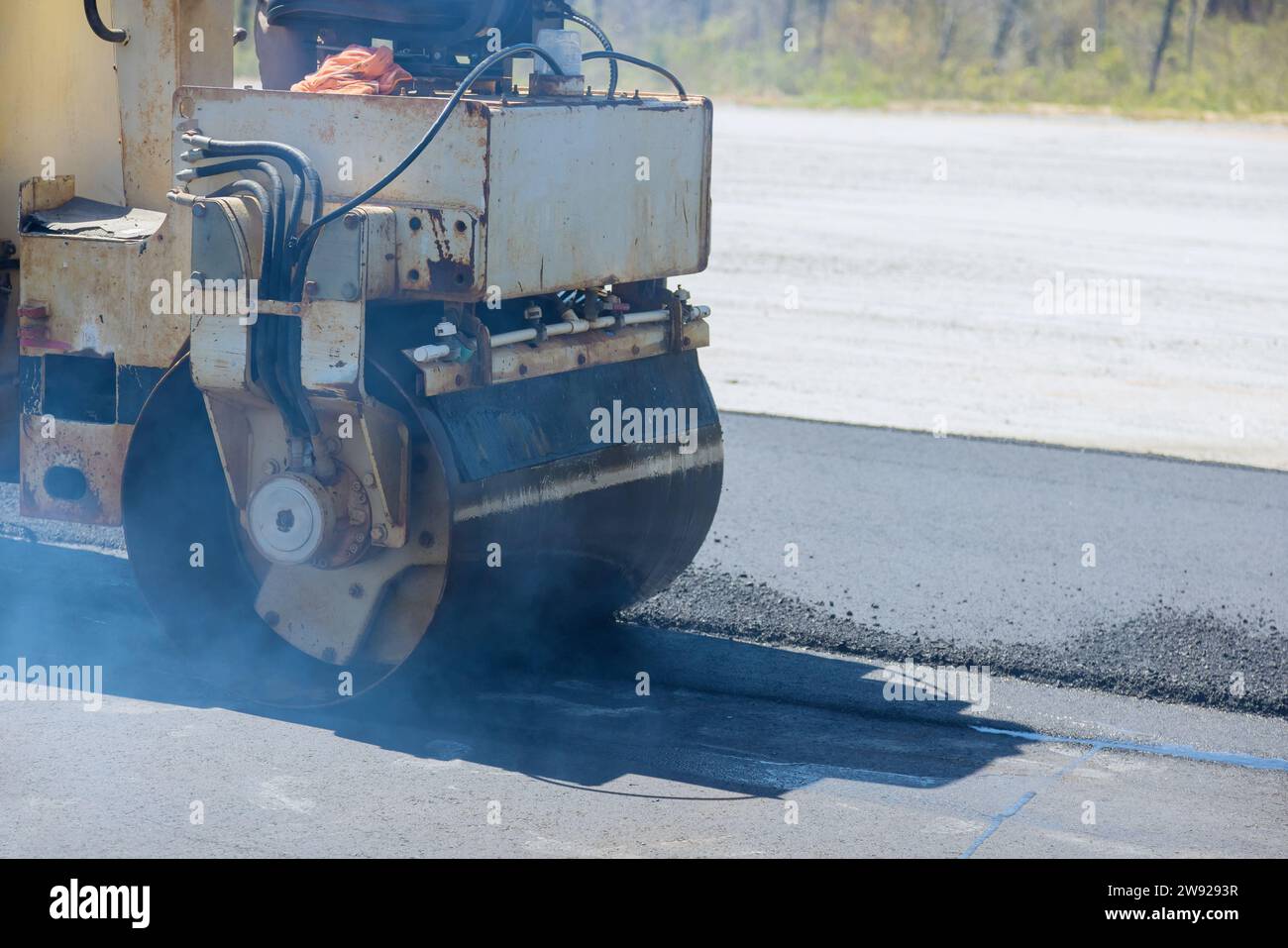 An asphalt roller compactor is used by worker during construction of ...