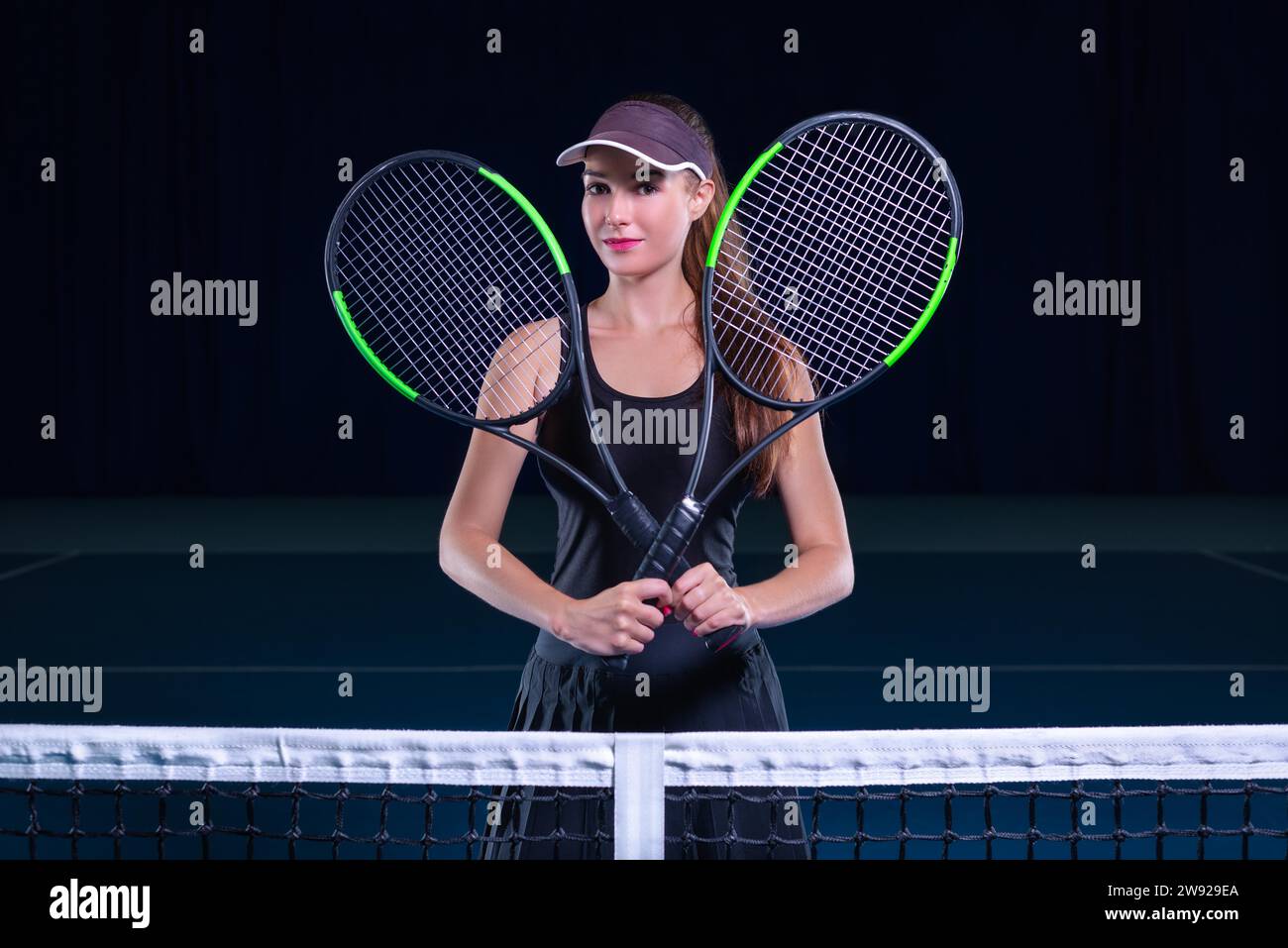 Portrait of a beautiful tennis player posing with two rackets on the ...