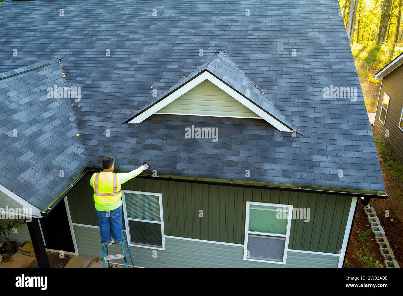 Using ladder, worker cleans debris, dirt, fallen leaves from clogged ...