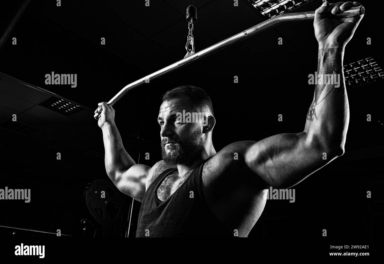 Professional athlete performs an exercise in the gym. Pulls the bar to ...