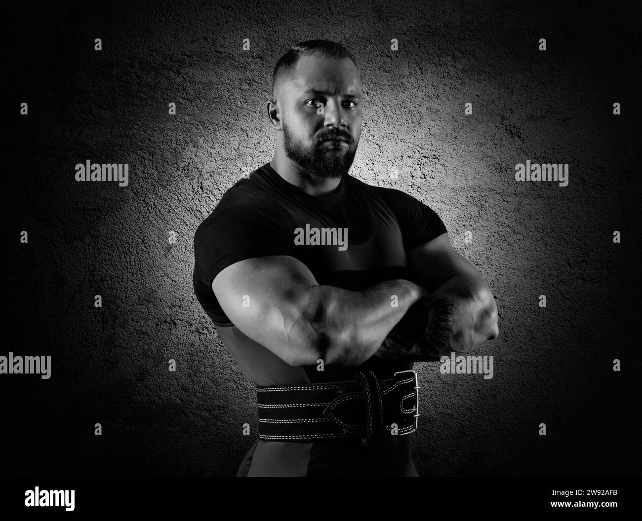 The weightlifter stands in a menacing pose with crossed huge arms and ...