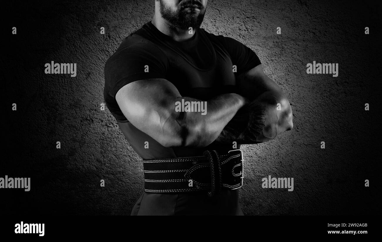 The weightlifter stands in a menacing pose with crossed huge arms and ...