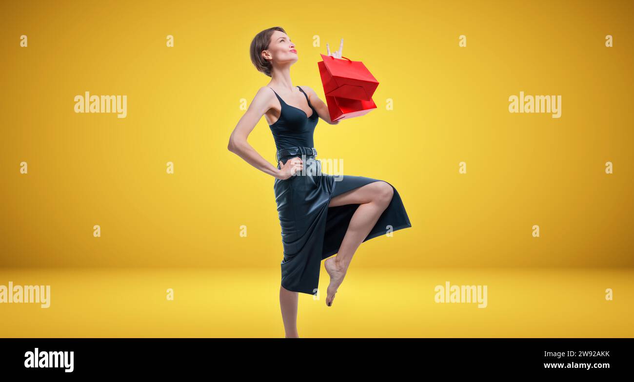 Stylish adult tall woman posing in studio with gift bags. Shopping ...