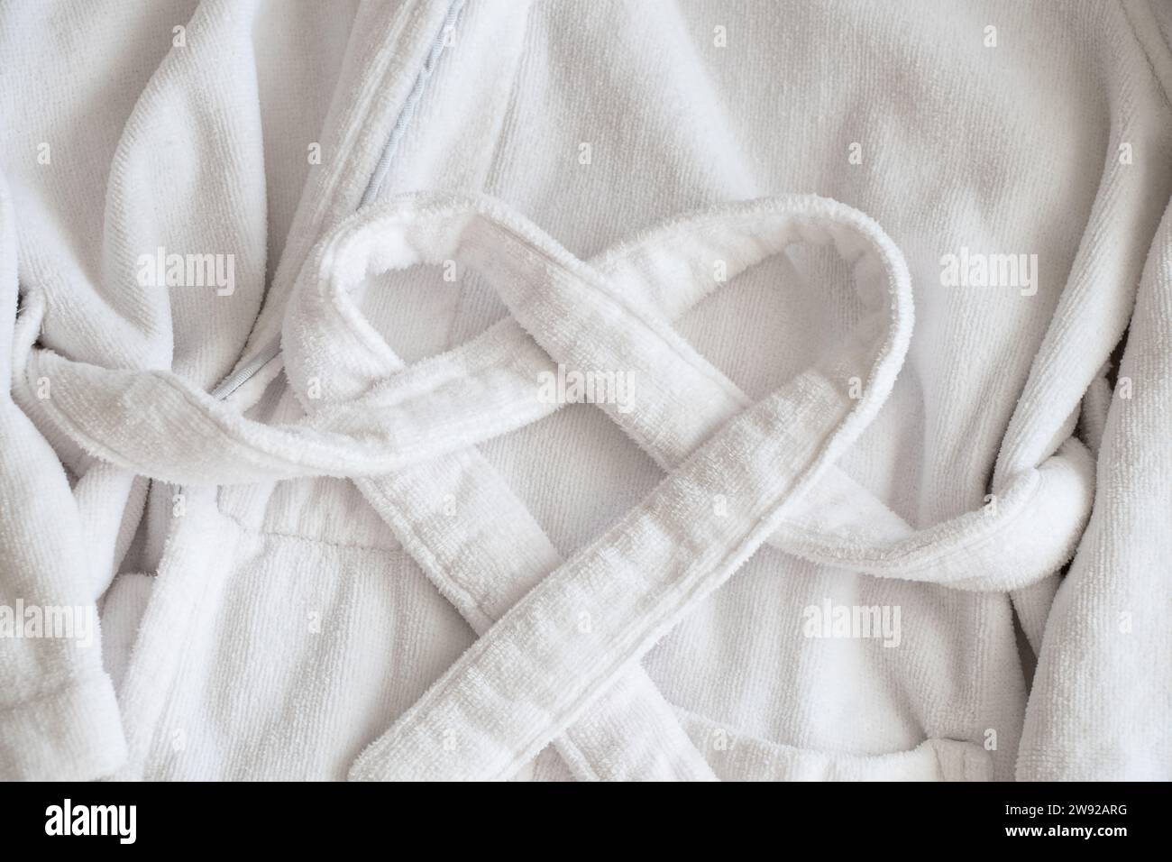 Women's white terry robe, clean, lying on the bed close-up, home white ...