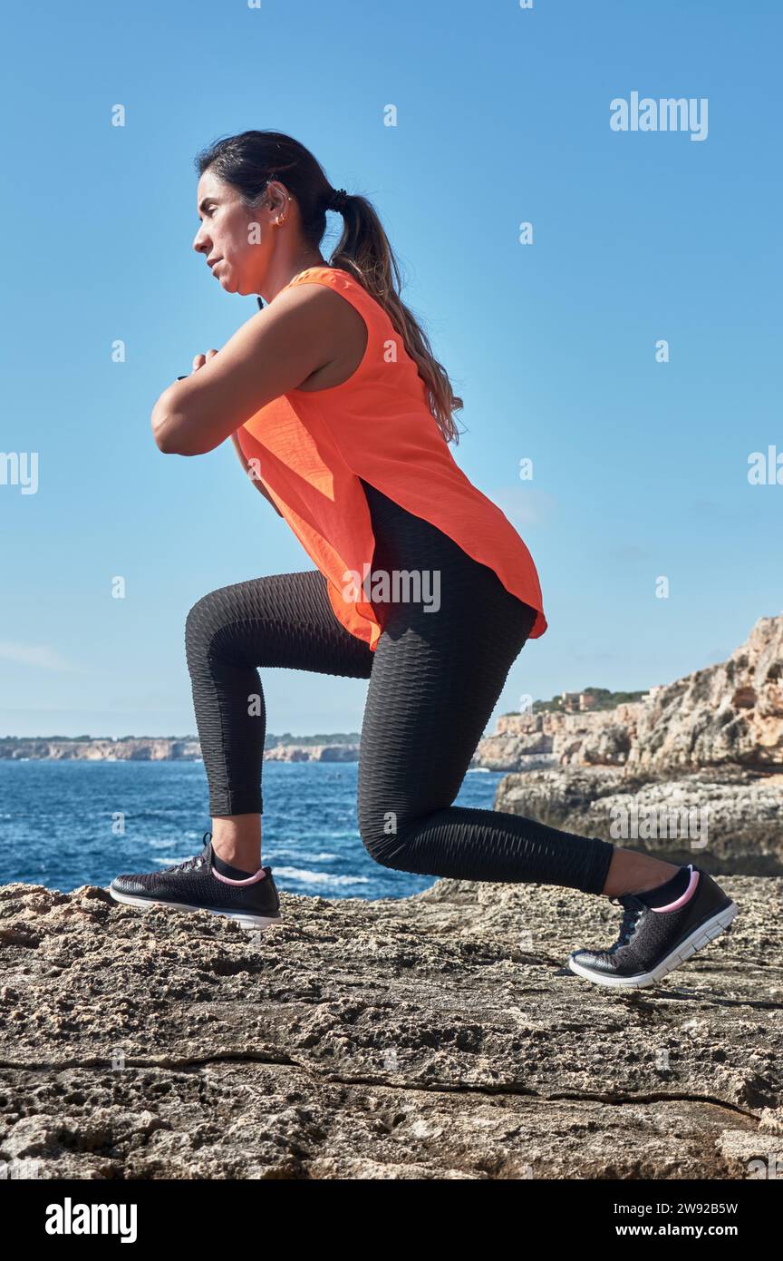 Latin woman, middle-aged, with orange top, black leggings, training ...