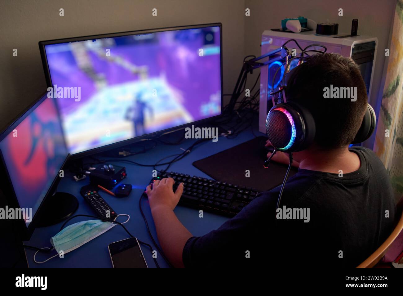 Back view of teenage gamer boy playing video games online on computer ...