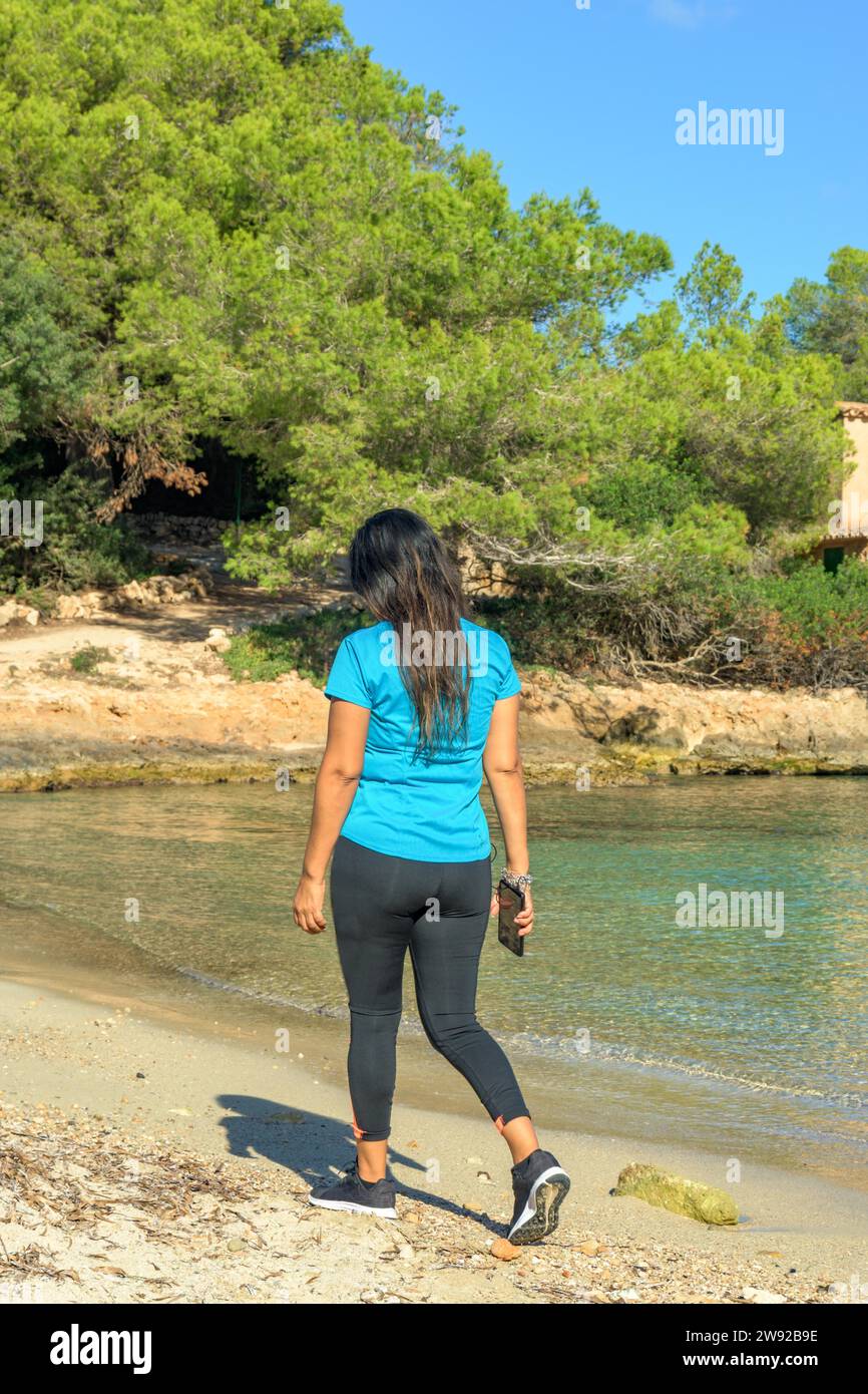 Latina woman in sportswear walking and listening to music with her ...