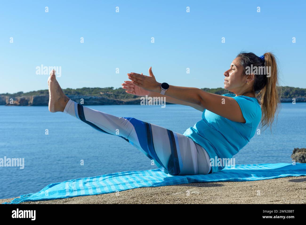 Middle-aged fitness woman outdoors in front of the sea does yoga ...